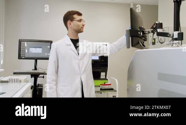 Handheld shot of man in lab coat and gloves checking test tube and ...