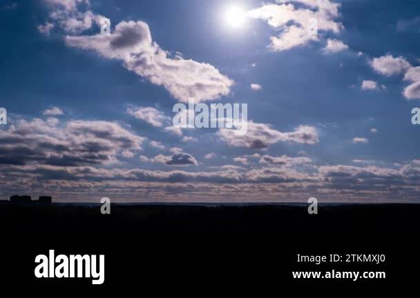 Cumulus clouds moving in the sky with sun over the horizon, timelapse ...