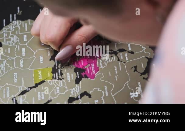 Woman scratching Europe countries on the surface of scratch world map ...