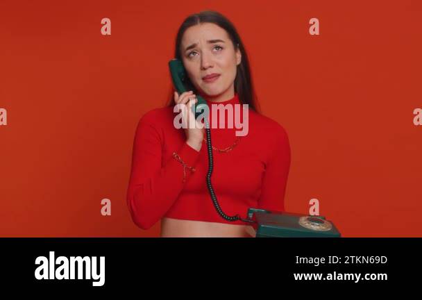 Bored, tired pretty young woman in crop top talking on wired vintage ...