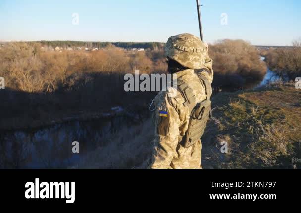 Dolly shot of young man in military uniform holds a waving flag of ...