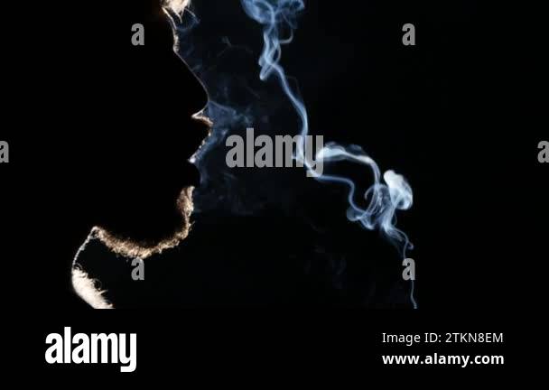 Man smokes a cigar. Takes a big drag and puffs smoke. Blacklight ...
