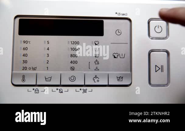 A man uses the power key to turn on a home automatic washing machine. A ...