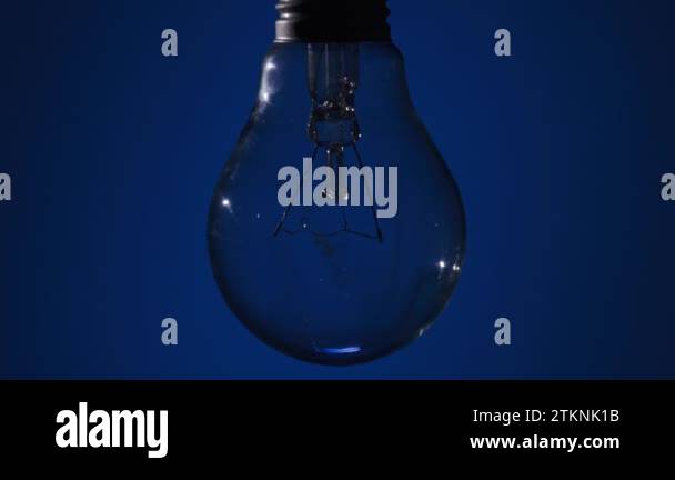 Incandescent lamp glows and flickers on dark blue background. Edison ...