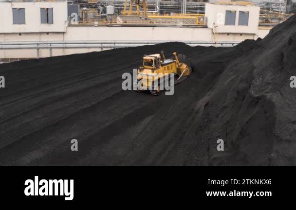 A crawler bulldozer rakes coal reserves into a large pile for heating ...