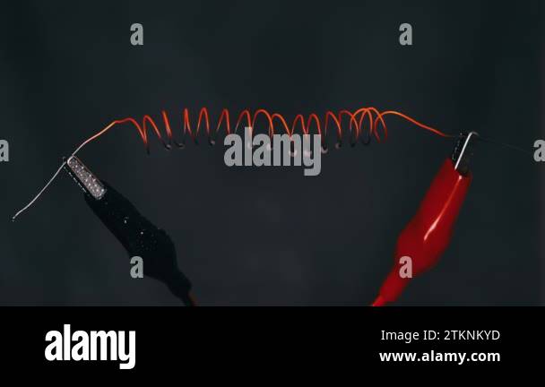 Nichrome filament connected to power wires is heated to red under the ...