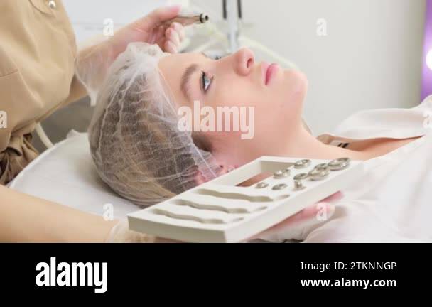 A dermatologist examines the skin on a young womans face. A beautician ...