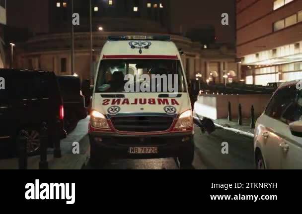Ambulance vehicle with flashers parked on the road at night in an old ...