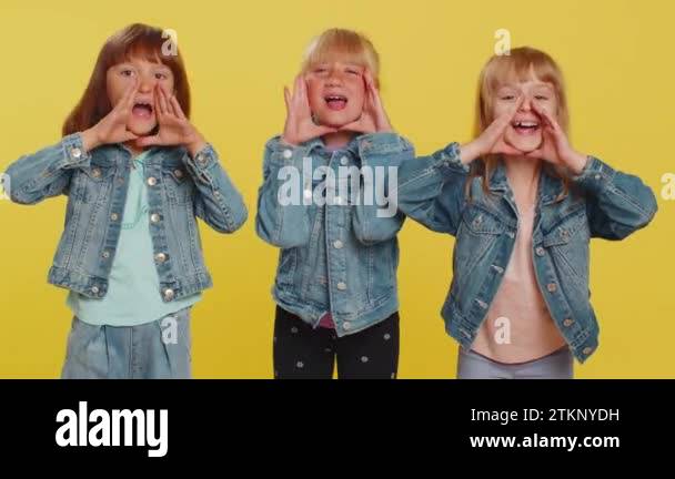 Expressive teenage girls holding hands near mouth loudly screaming ...