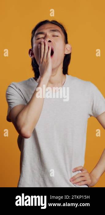 Vertical video: Drained person yawning and being tired in studio ...