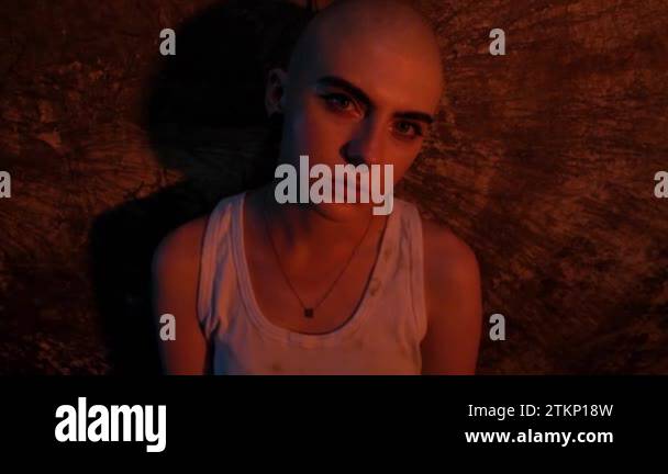 A woman with no hair on her head in a neon-lit basement is drawn behind ...