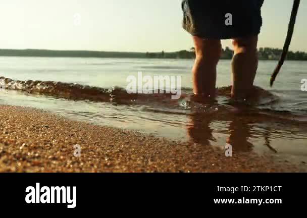 Waves of water crash against sandy beach. The child stands ankle-deep ...