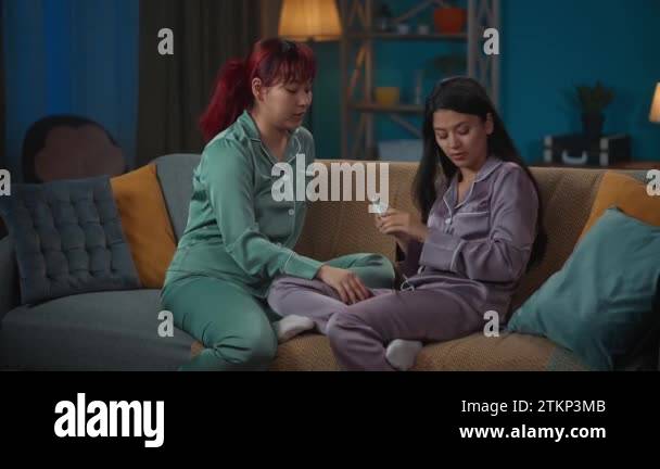 Medium-full video capturing two young women in pajamas sitting on the ...