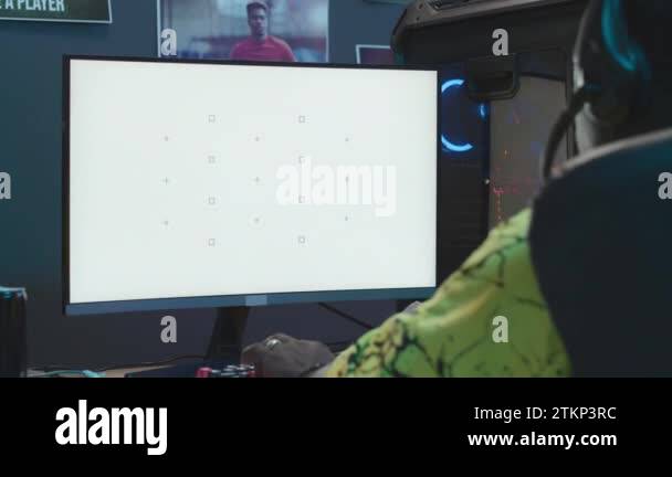 Over-the-shoulder shot of anonymous dark-skinned gamer sitting in front ...