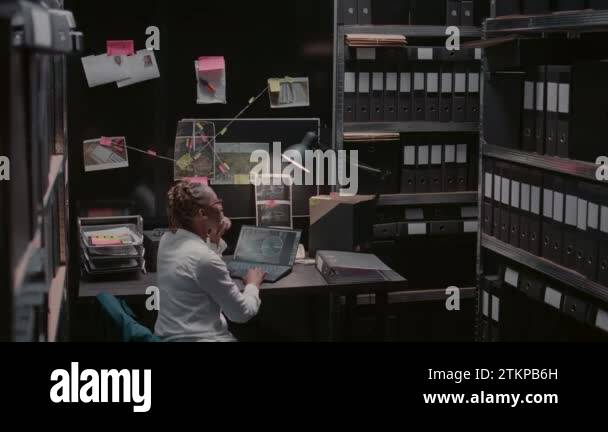 Law enforcement agent reading archive records at desk, conducting ...