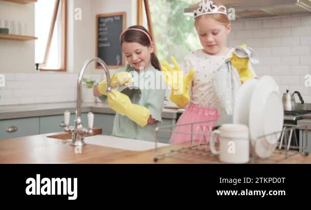 Children, learning and cleaning dishes in kitchen with sister, girl or ...