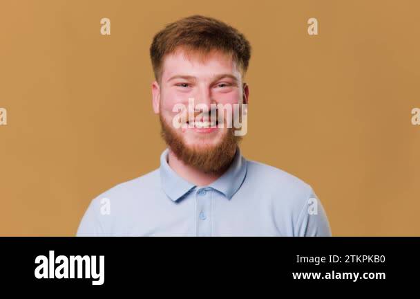 A teenage guy with fiery red hair strikes a pose in the photo studio ...