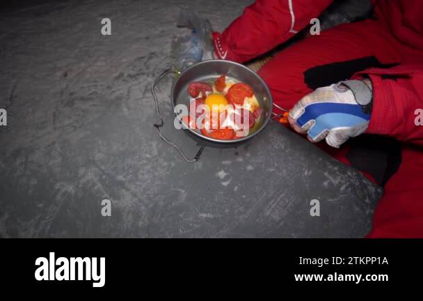 A guy cooks food on gas inside an ice cave. The climber lights the ...
