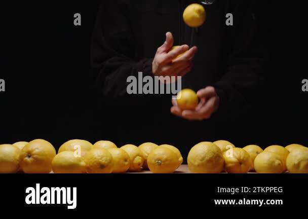 The whole table is covered in lemons. The man starts juggling or, but ...