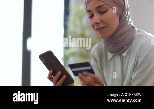 Great mobile banking service. Young happy muslim woman in hijab paying ...