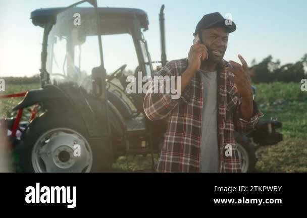 African American man arguing by phone. Angry farmland worker making ...