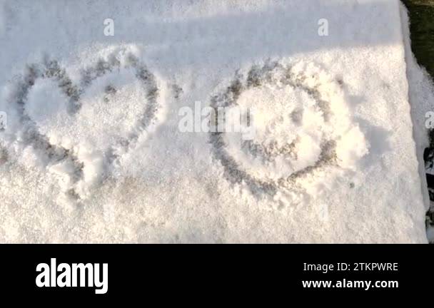 drawing in the snow. man draw on the snow. Child drawing heart shape on ...