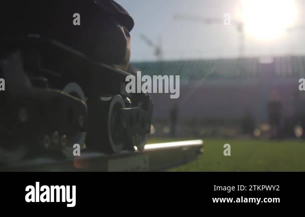 Adjusting of camera on metal rails on football stadium illuminated by ...