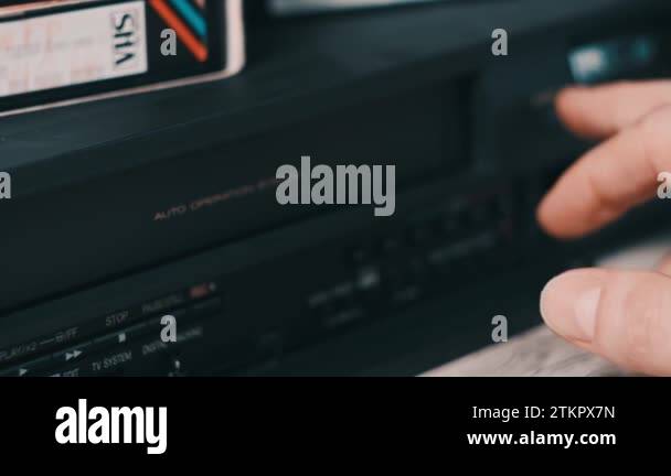 Eject VHS tape cassette from VCR player. Male hand pushes a button and ...