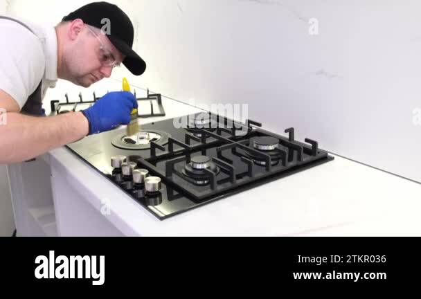 A professional craftsman installs a gas stove in a beautiful white ...