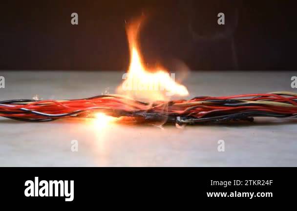 Twisted electric wires are burning and sparking on a dark background. A ...