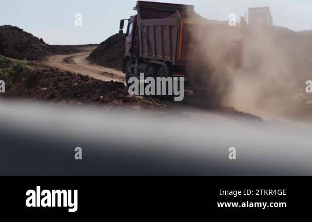 Loaded tipper truck drives along ground road in quarry. Lorry ...