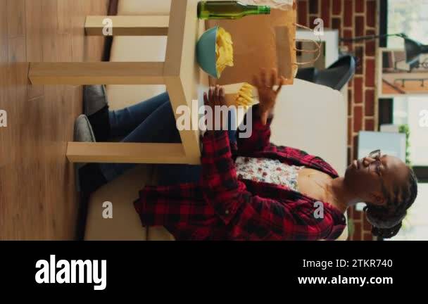 Vertical video: Young adult taking out hamburger and fries, eating fast ...