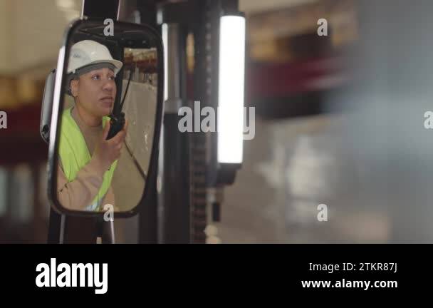Through rear view forklift mirror shot of young Biracial female ...