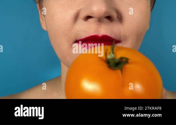 Unrecognizable young woman vibrantly colored lips bites into yellow ...