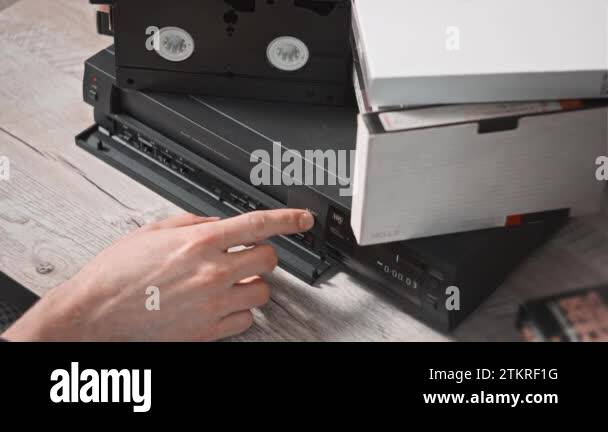 Eject VHS tape cassette from VCR player. Male hand pulls out VHS from a ...