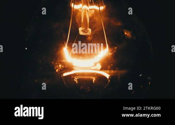 Incandescent filament close-up glows and flickers on a black background ...