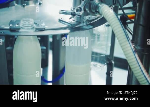Plastic bottles filling with milk. Milk pouring into plastic bottle at ...