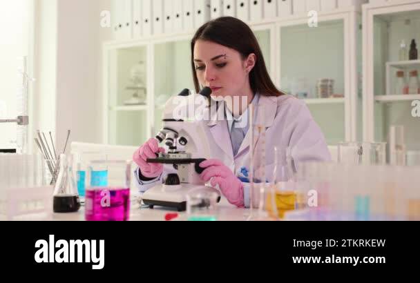 Scientist with microscope, test tubes laboratory glassware and reagents ...