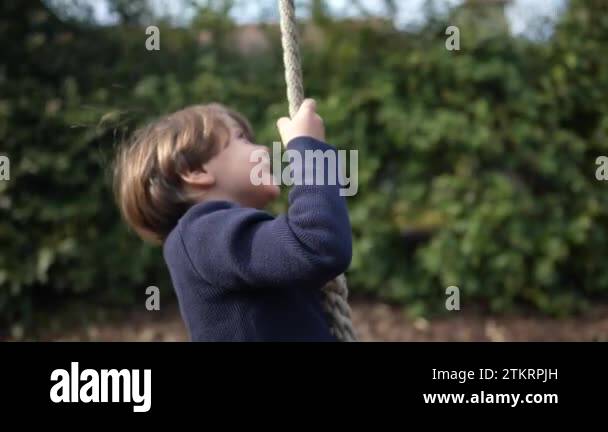 Child sliding down on wire rope reaching the end of the line - holding ...