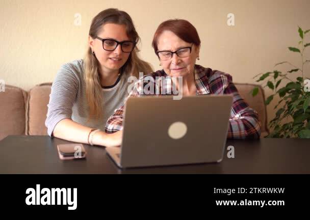 Granddaughter tells her old grandmother how to use a laptop. Teaches ...
