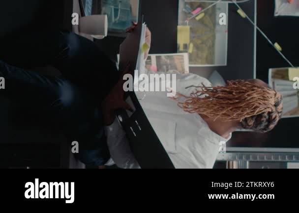 Vertical video: Two police officers looking at detective evidence map ...