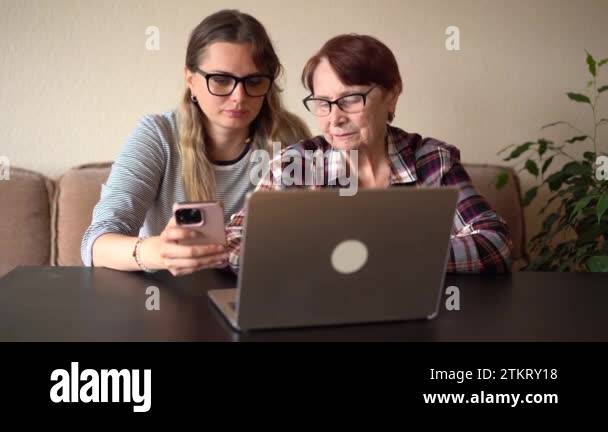 Granddaughter tells her old grandmother how to use a laptop. Teaches ...