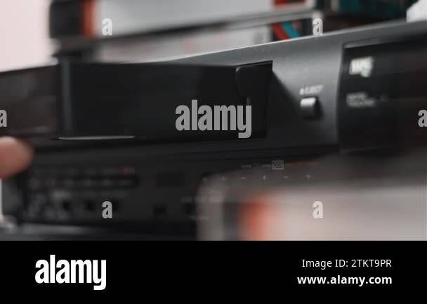 Male hand inserts VHS cassette into a VCR Video recorder. Black vintage ...