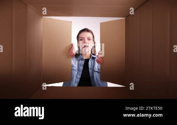 Young girl unpacking, opening cardboard box and looking inside. Sad ...