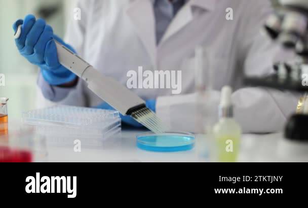 Laboratory worker drops liquid using special tool into container ...