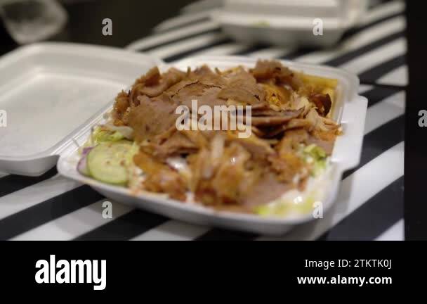 Man eats kebab with fork close-up. White plastic box package with doner ...