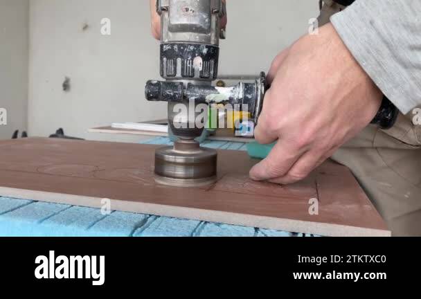 Worker tiller drills round hole in porcelain tile with a diamond core ...
