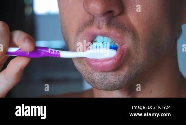 Extreme close up male brushing teeth with manual toothbrush in bathroom ...