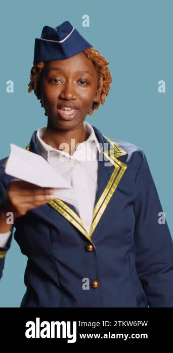 Vertical video: Female model showing folded airplane in studio, playing ...