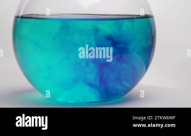 Spreading of dark blue chemical reagent. Liquid in flask changing color ...